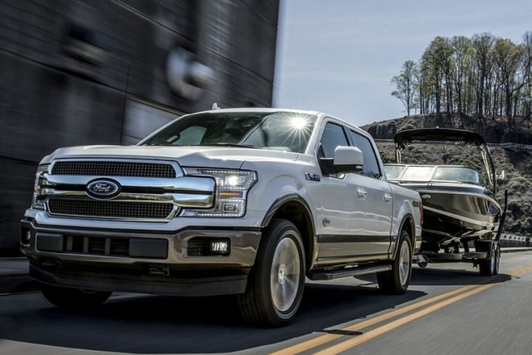 2020 Ford F-150 King Ranch towing a boat down road from exterior front ...