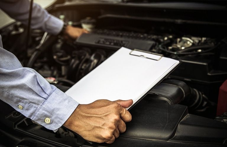 A man holding a checklist in front of a car.